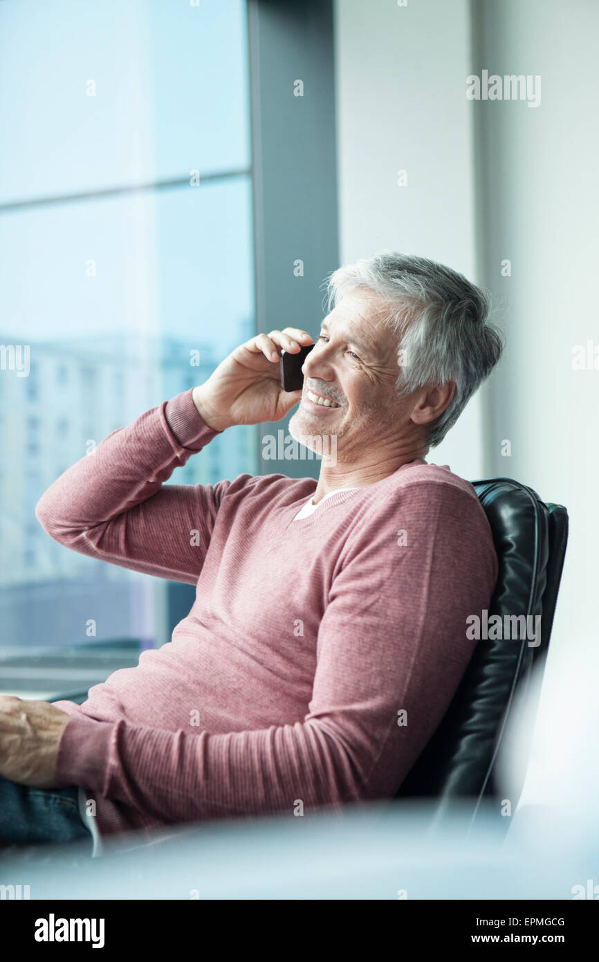 Man sitting in a leather chair telephoning with smartphone Stock Photo ...