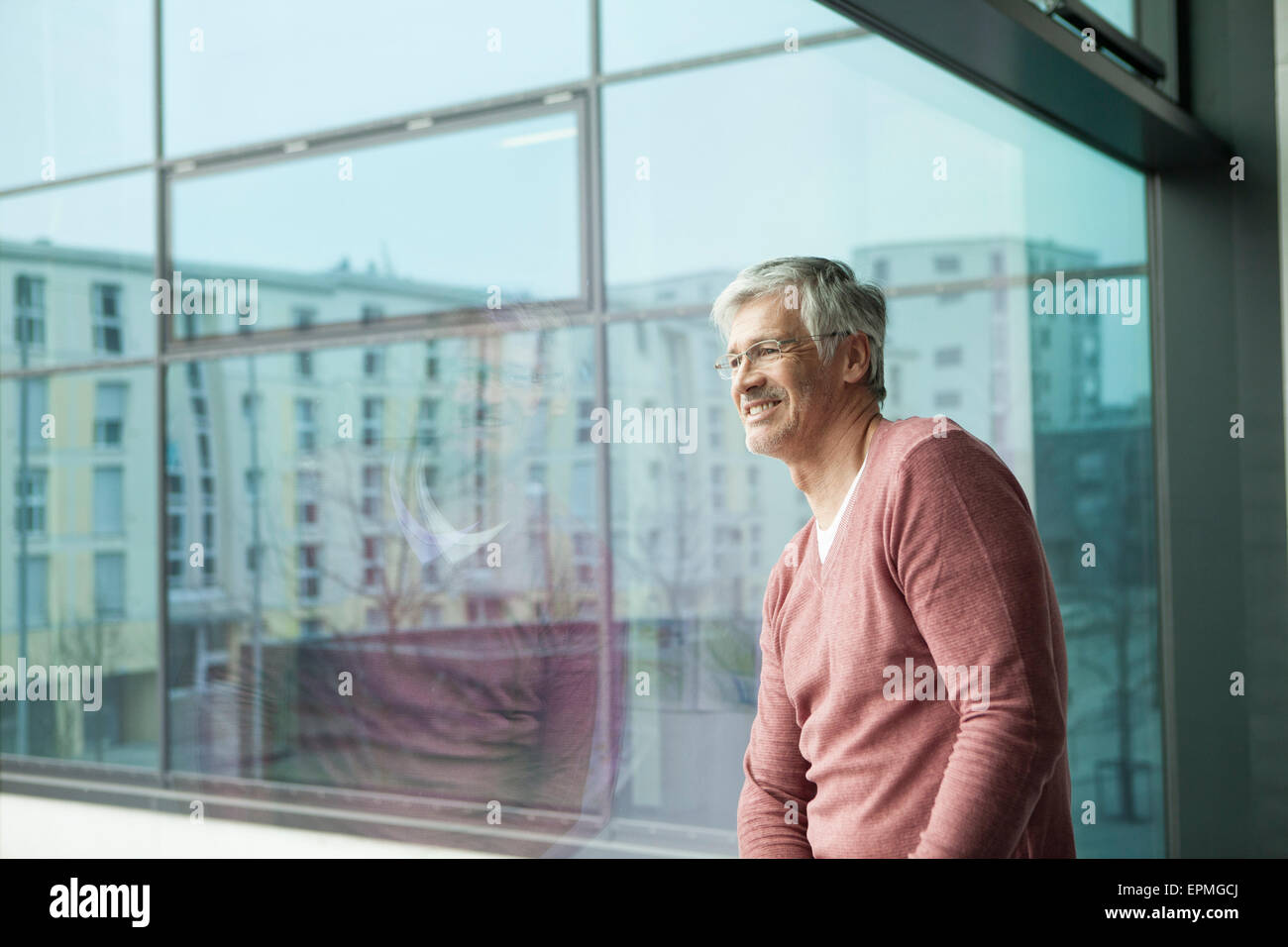 Smiling man looking through window Stock Photo - Alamy