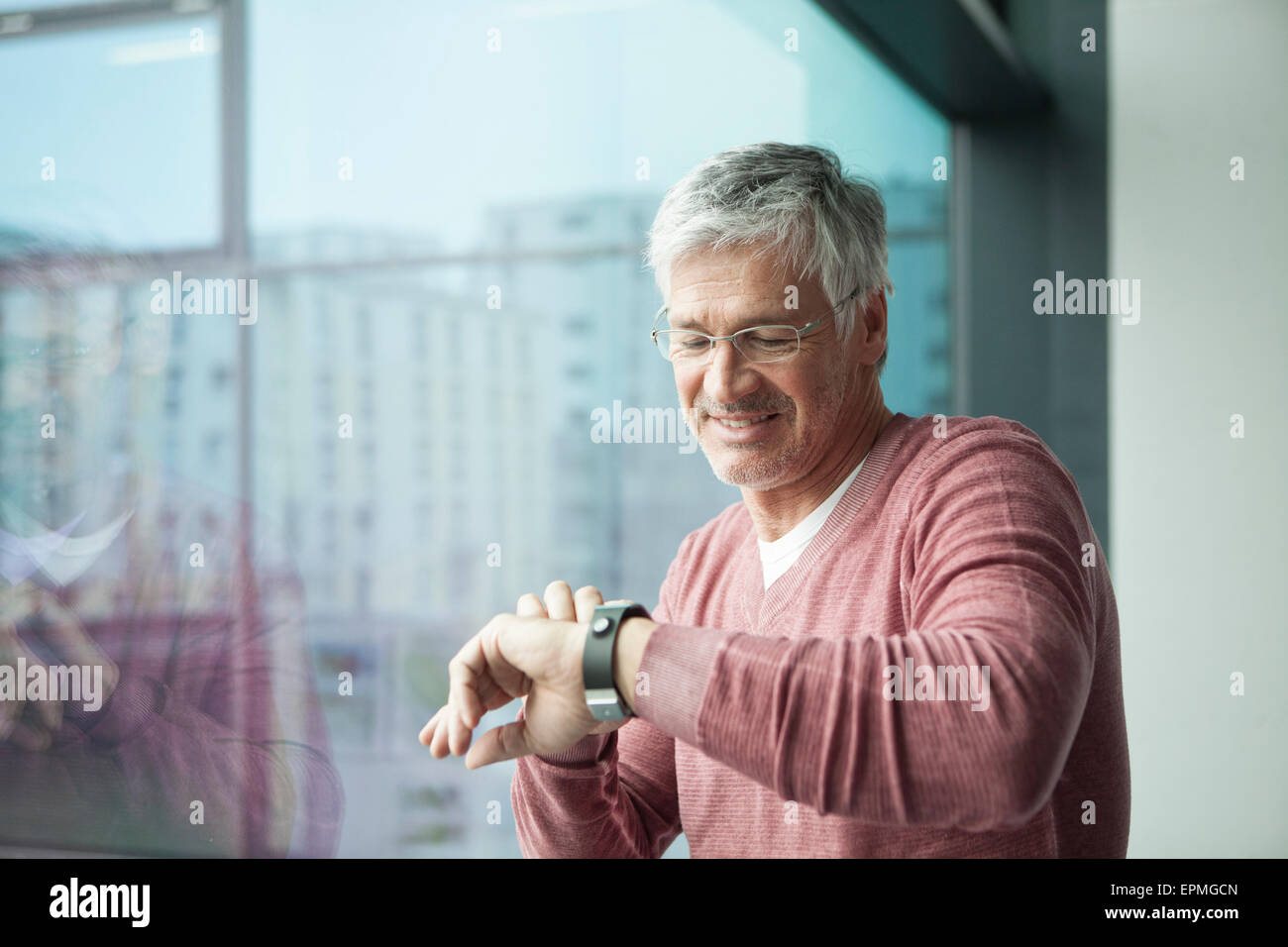 Smiling man looking at his smartwatch Stock Photo - Alamy