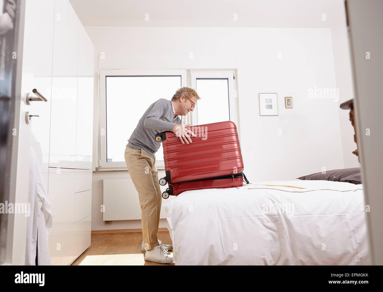 Senior man packing suitcase in bedroom Stock Photo - Alamy