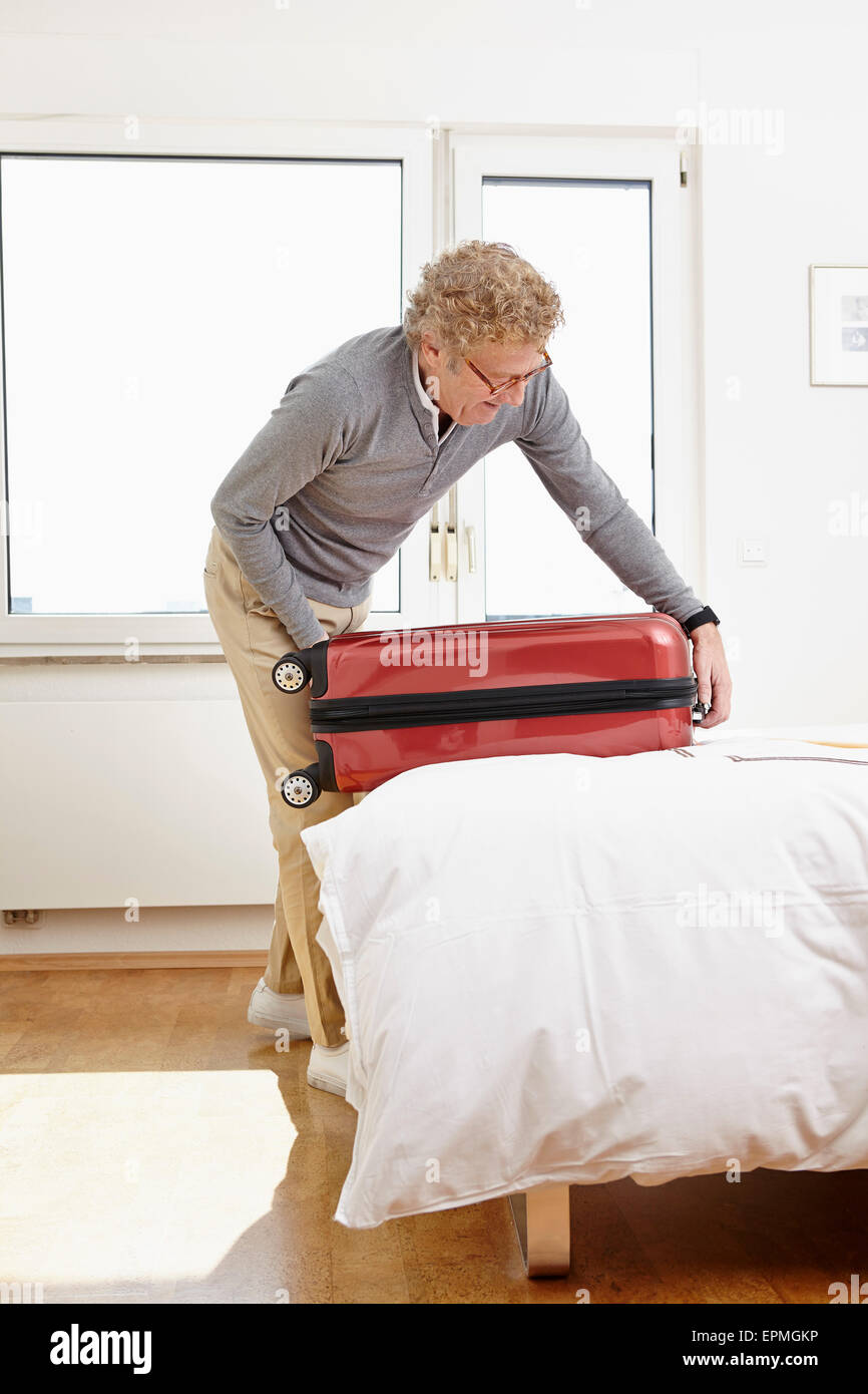Senior man packing suitcase in bedroom Stock Photo - Alamy