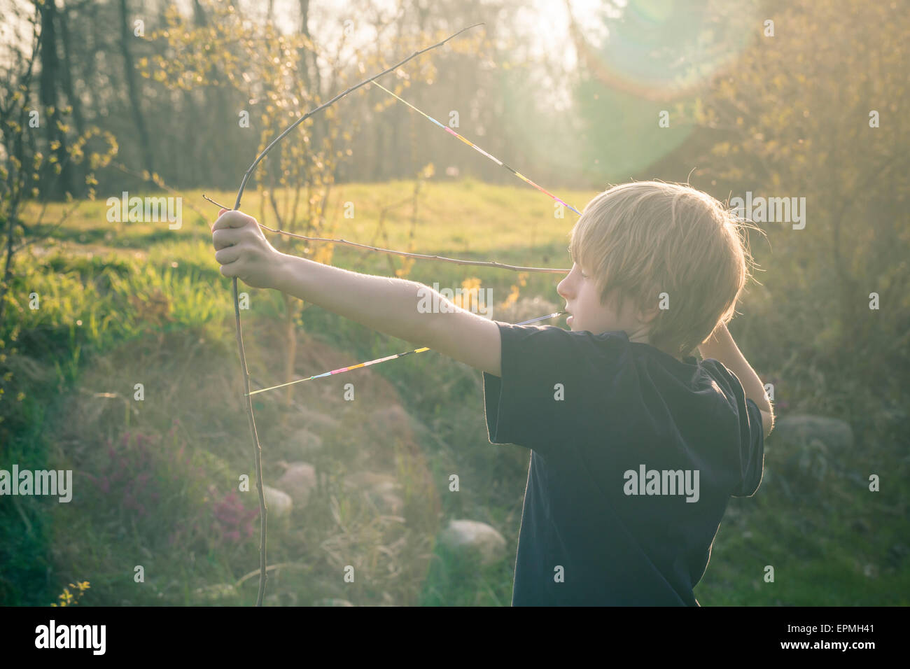Boy using bow self-built of twigs and looms Stock Photo - Alamy