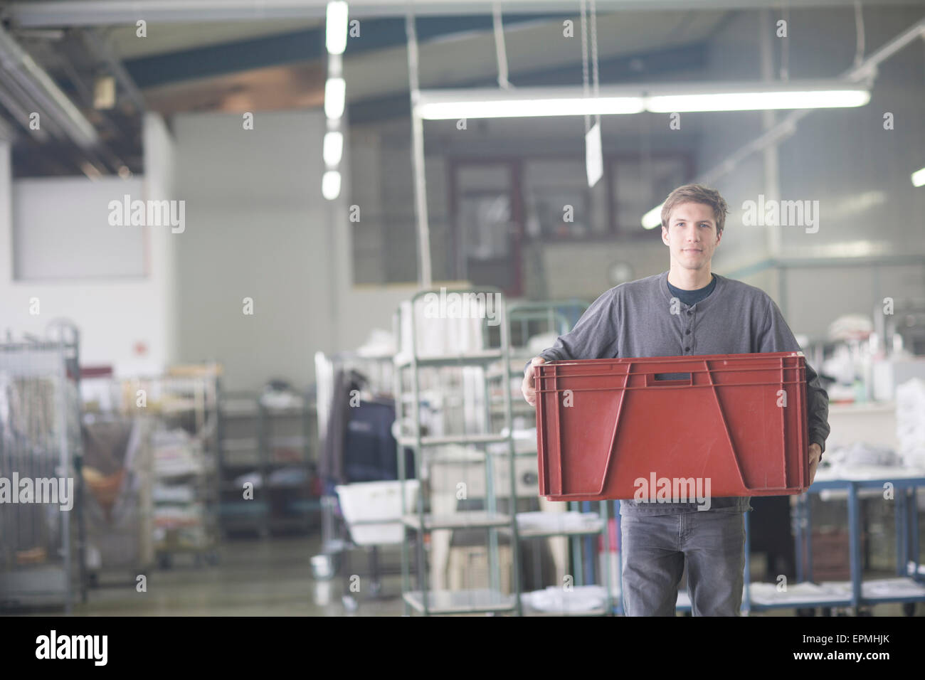Worker in factory carrying box Stock Photo - Alamy