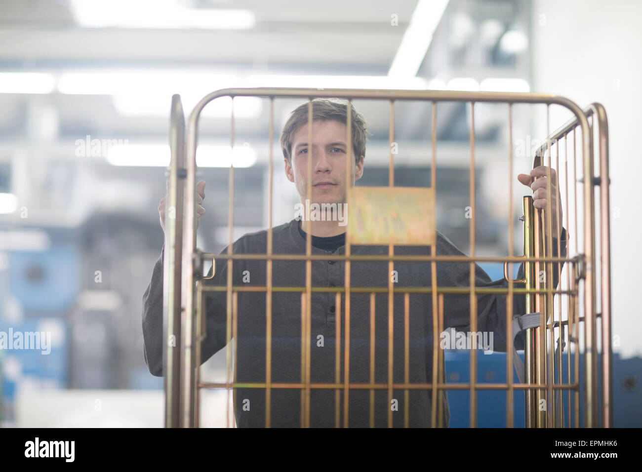 Man in factory pushing trolley Stock Photo - Alamy