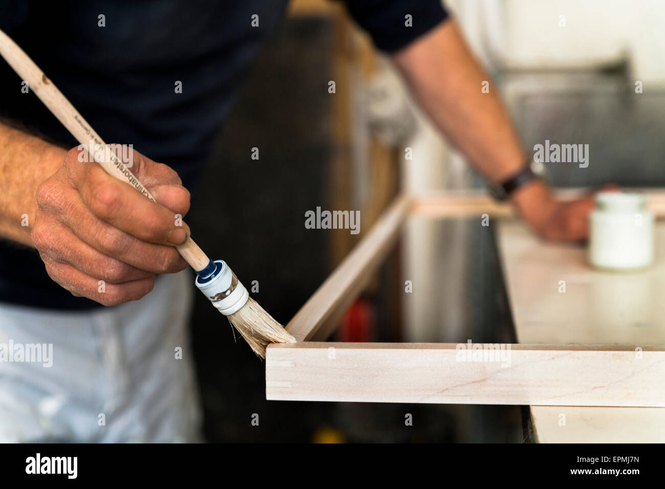 Frame-maker in workshop painting a wooden frame Stock Photo - Alamy