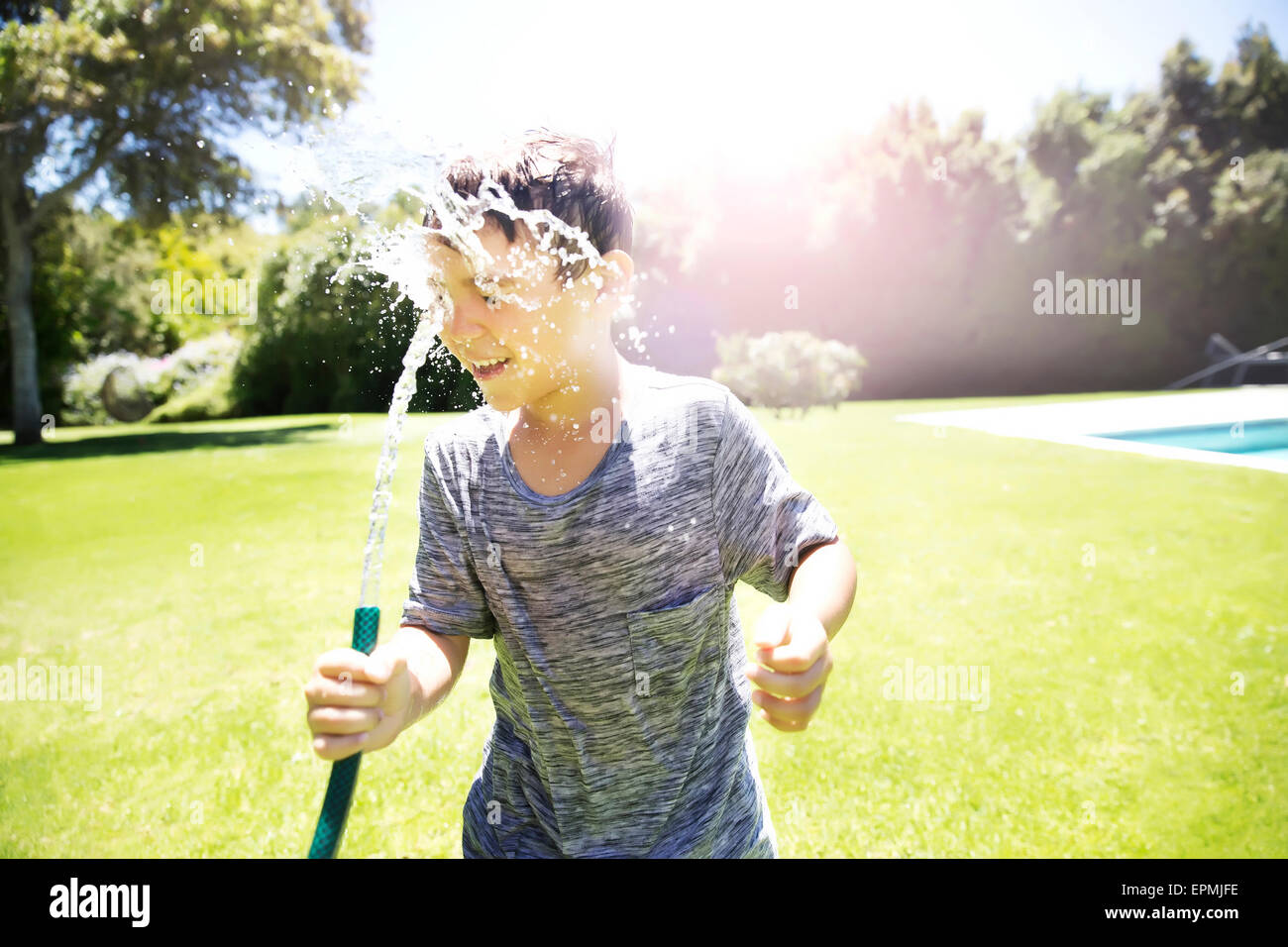 Boy splashing water with garden hose Stock Photo - Alamy