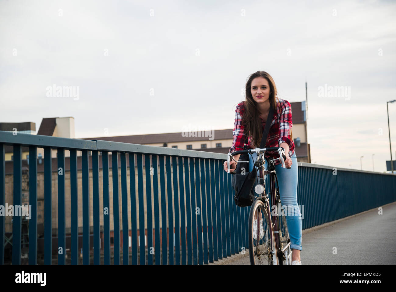 Young woman riding bicycle on bridge Stock Photo - Alamy