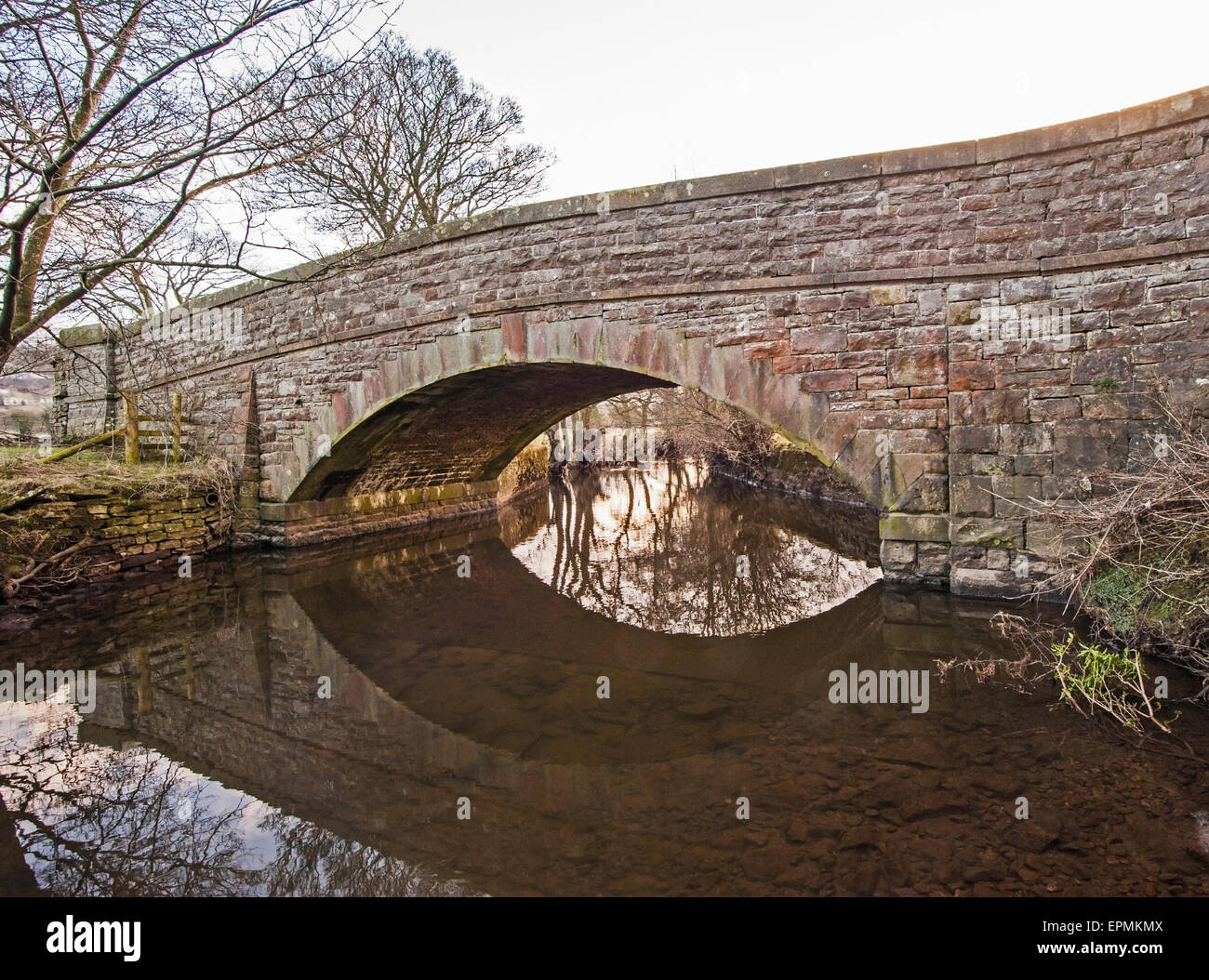Old arched stone bridge in english rural countryside setting over small ...