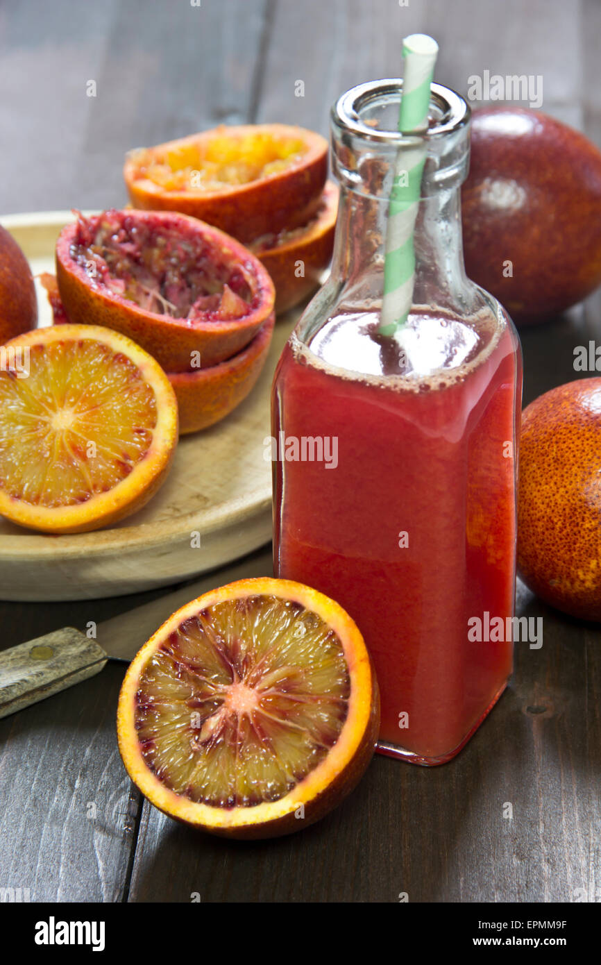 Glass bottle of blood orange juice, whole, sliced and squeezed blood ...