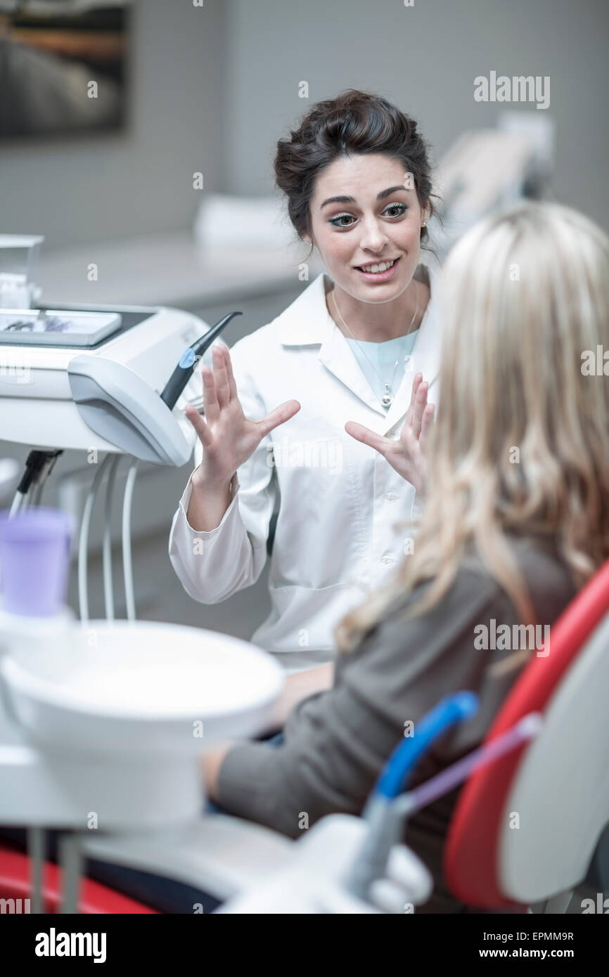 Dentist explaining procedure to patient sitting in dentist's chair ...