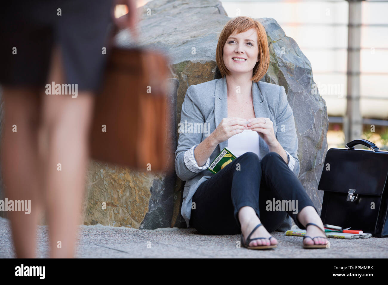 Businesswoman taking a break, sitting on ground rolling cigarette Stock ...