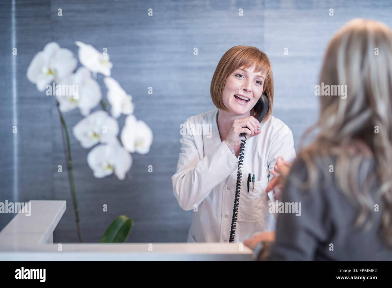 Receptionist greeting patient while on the phone Stock Photo - Alamy