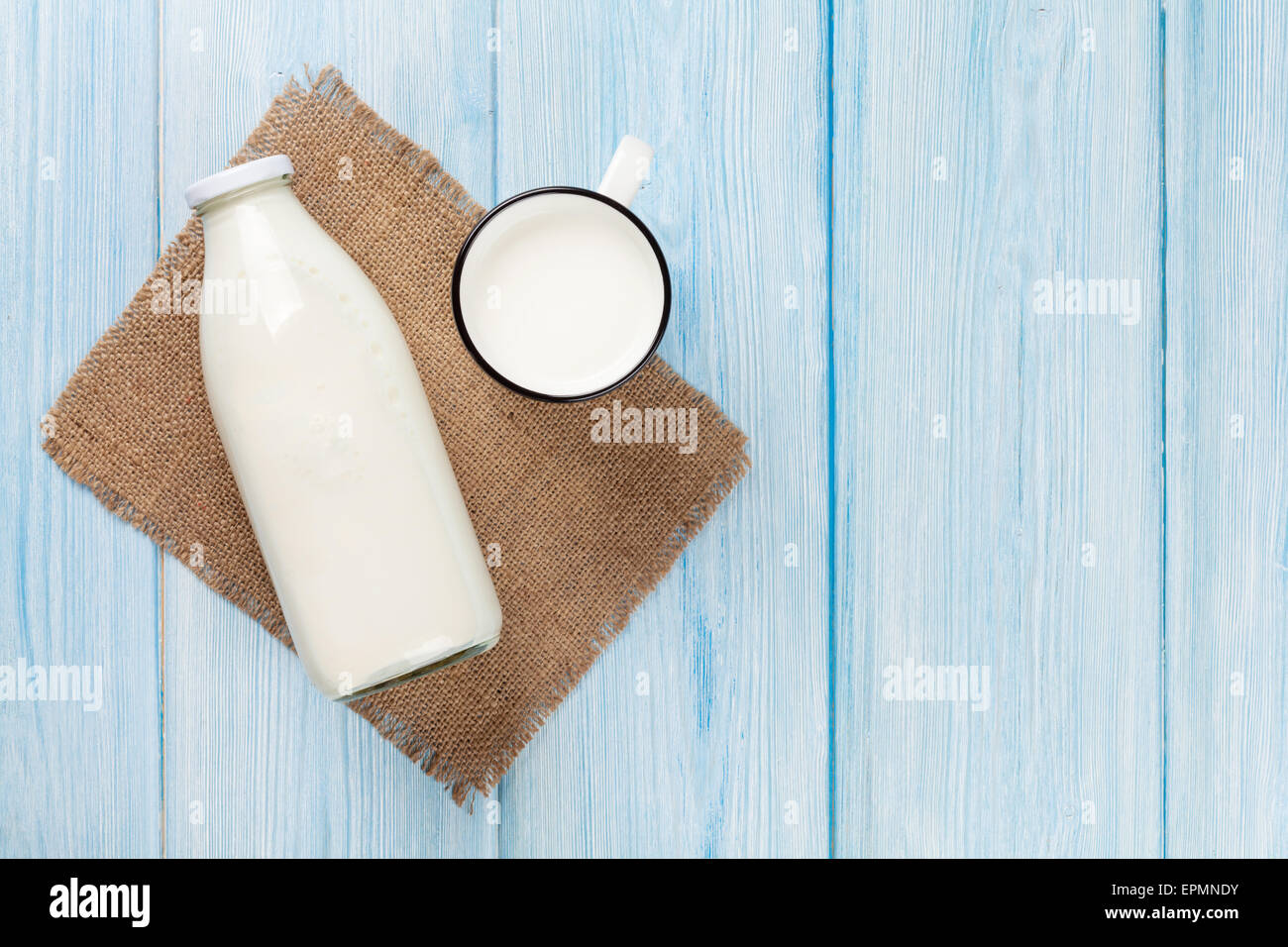 Milk cup and bottle on blue wooden table. Top view with copy space ...
