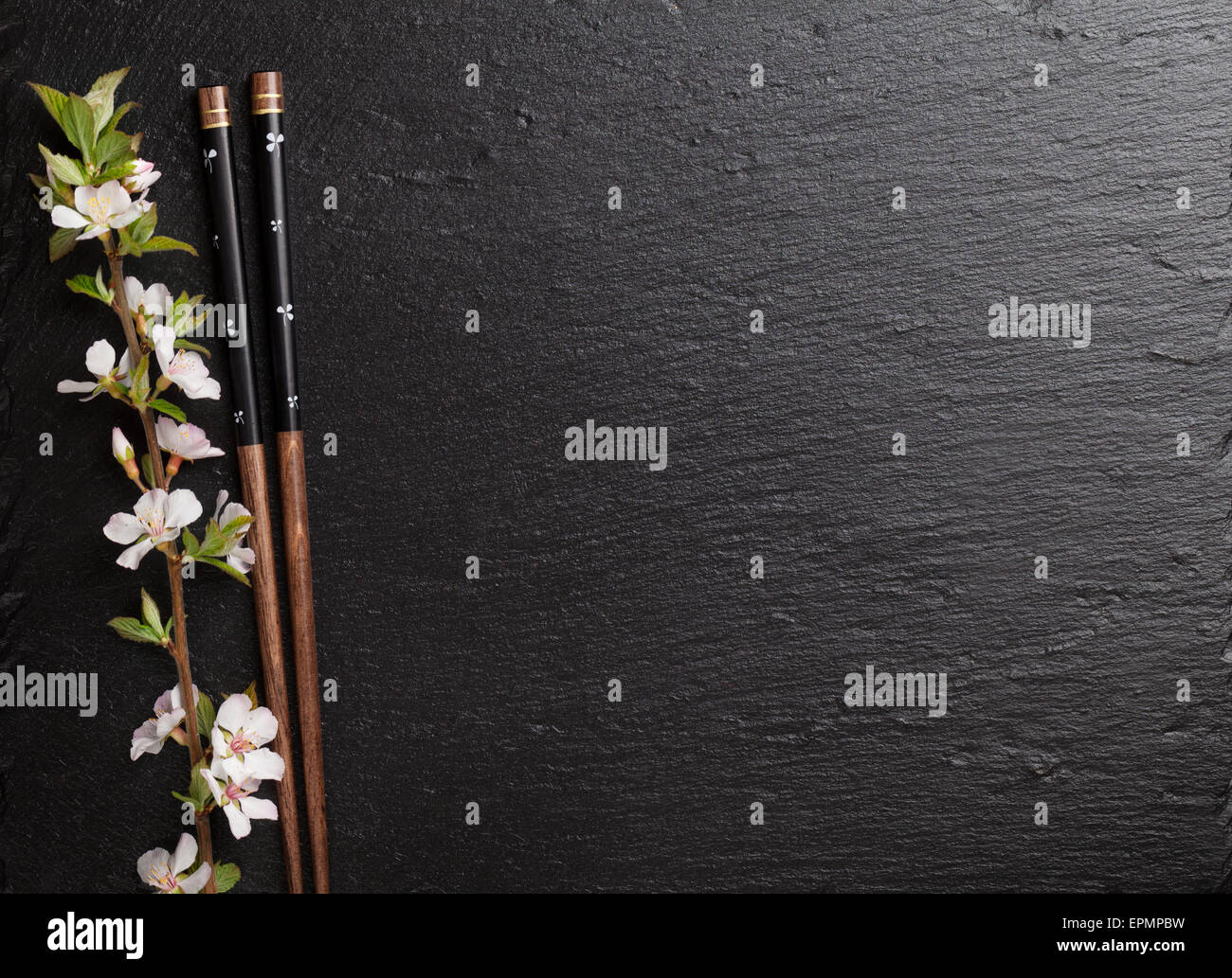 Japanese sushi chopsticks and sakura blossom on black stone background ...
