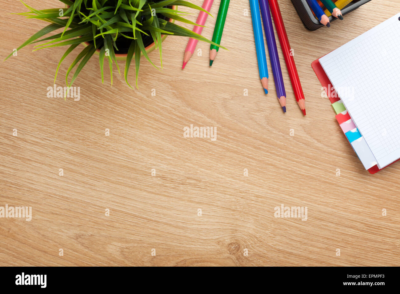 Office table with flower, blank notepad and colorful pencils. View from ...