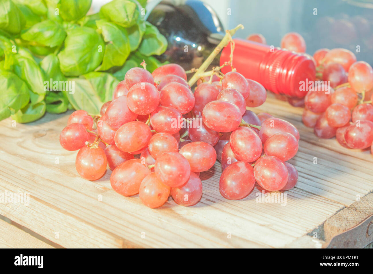 Purple, red grapes, in front of basil and red wine Stock Photo - Alamy