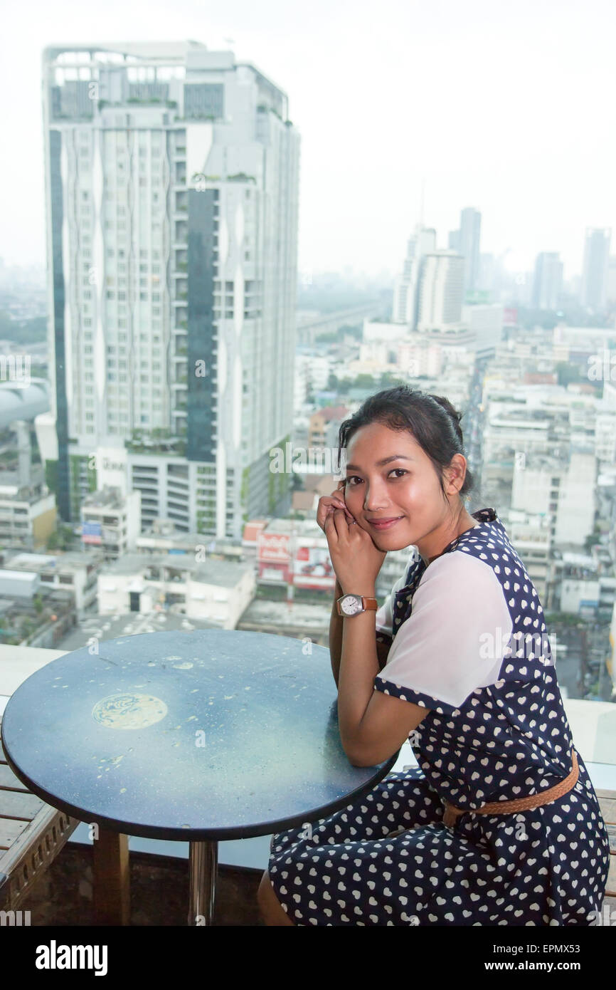 Young woman sitting at a table next to the window in a skyscraper Stock ...