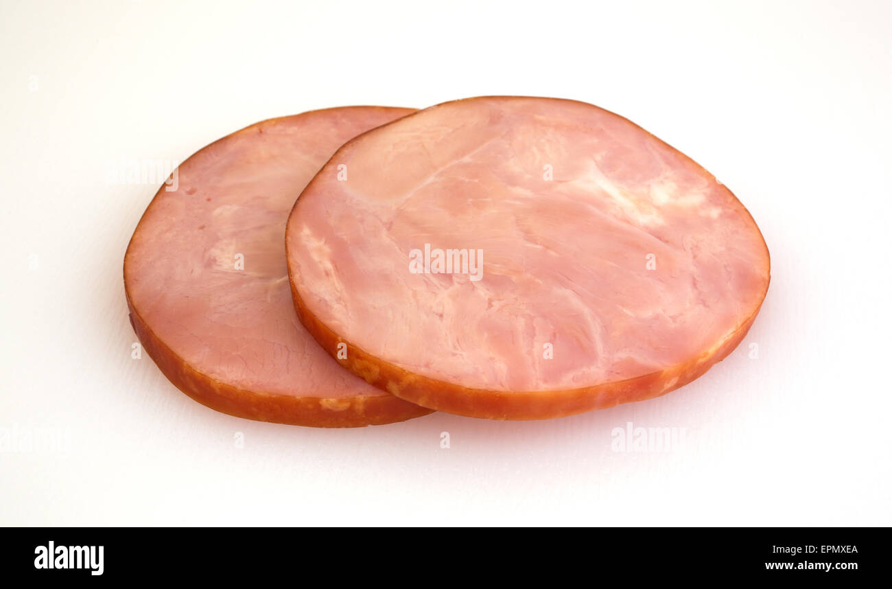 Two slices of ham on a white cutting board illuminated by natural light ...