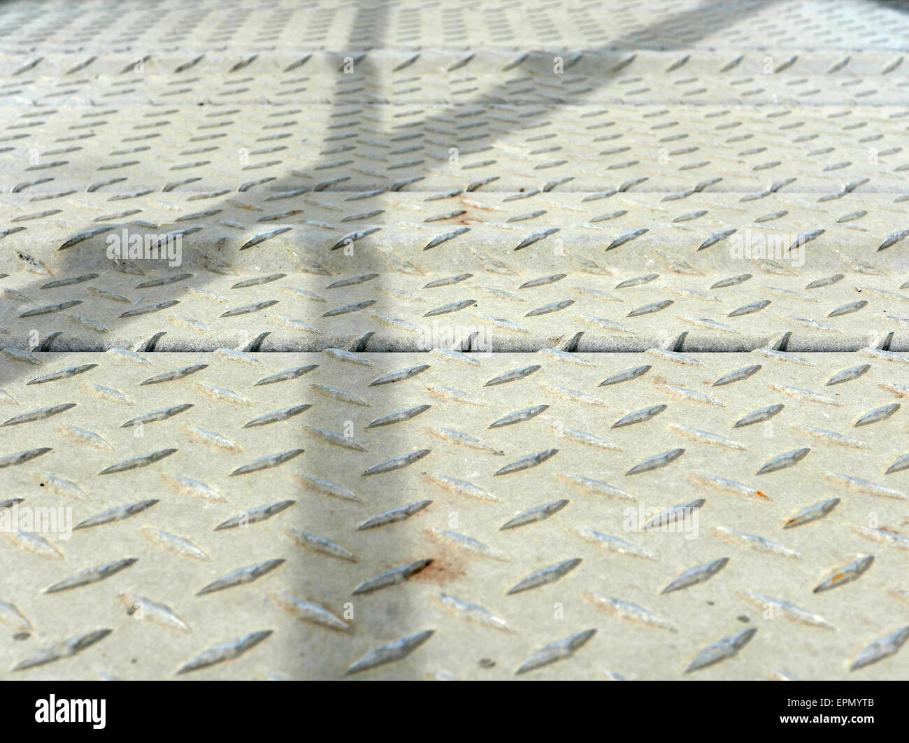 Close view of a steel non-slip walkway with the shadows of the railings ...