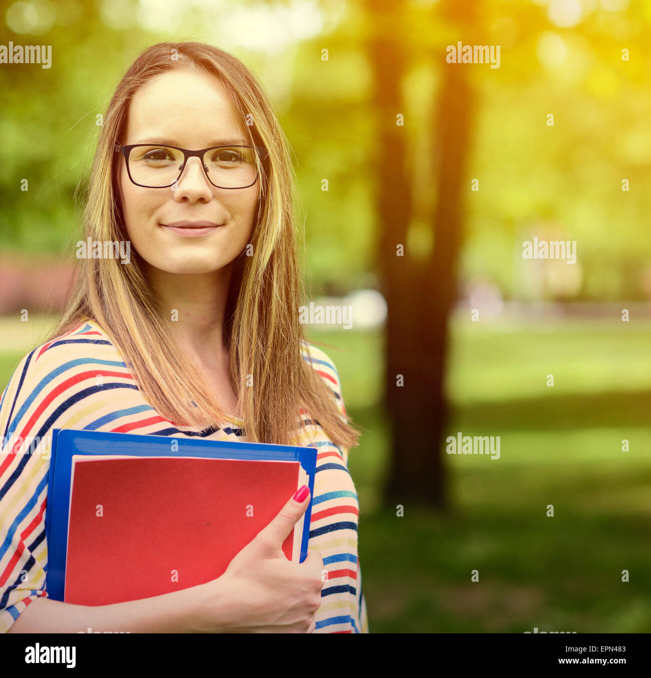 Young happy student woman with the book in her hands is standing and ...