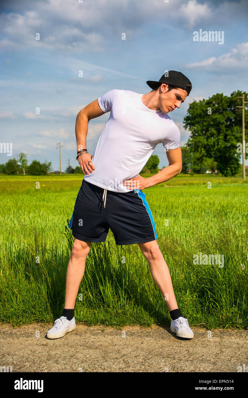 Athletic, handsome fit young man outdoor in country doing stretching ...