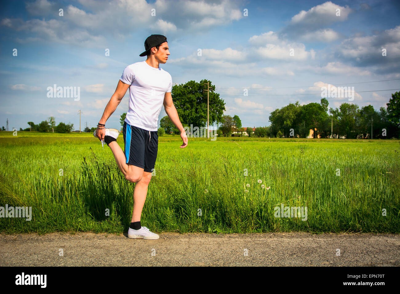Athletic, handsome fit young man outdoor in country doing stretching ...