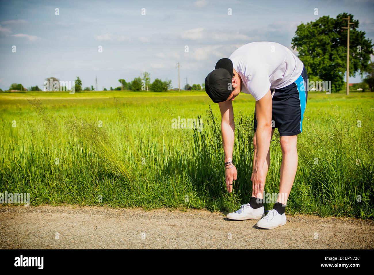 Athletic, handsome fit young man outdoor in country doing stretching ...