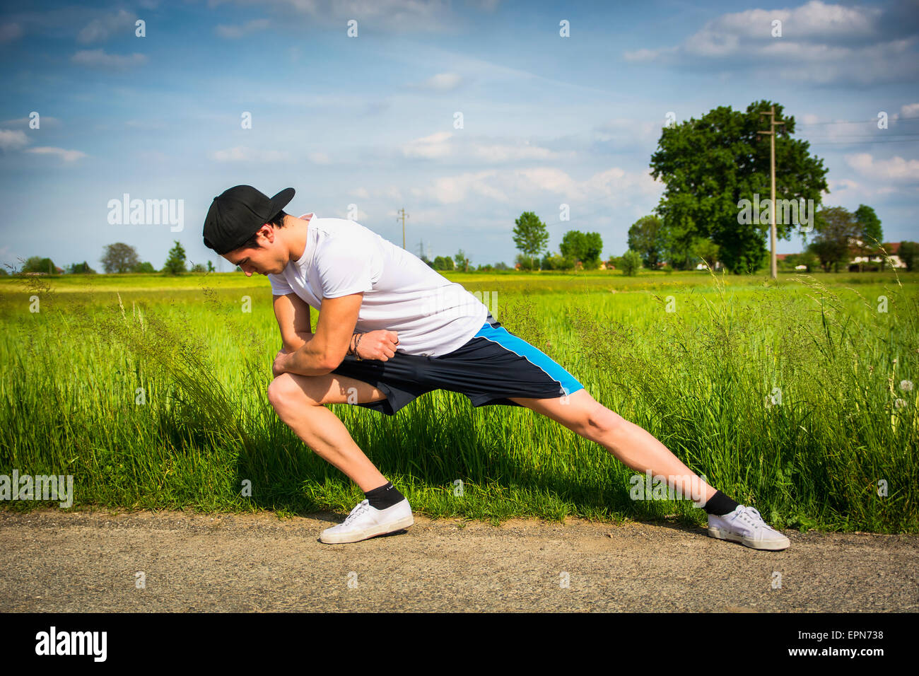 Athletic, handsome fit young man outdoor in country doing stretching ...