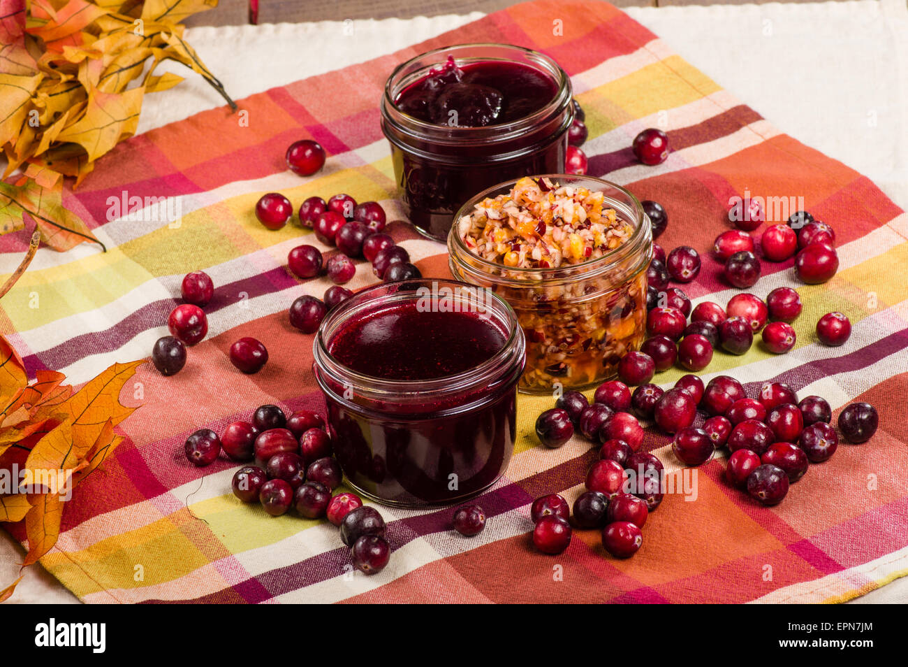 Jars of cranberry sauce with cranberries and fall leaves on a table ...