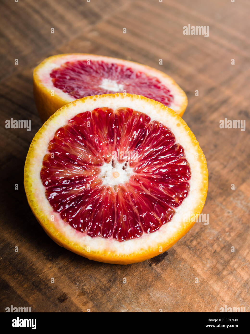 Blood orange halves on a wooden table Stock Photo - Alamy
