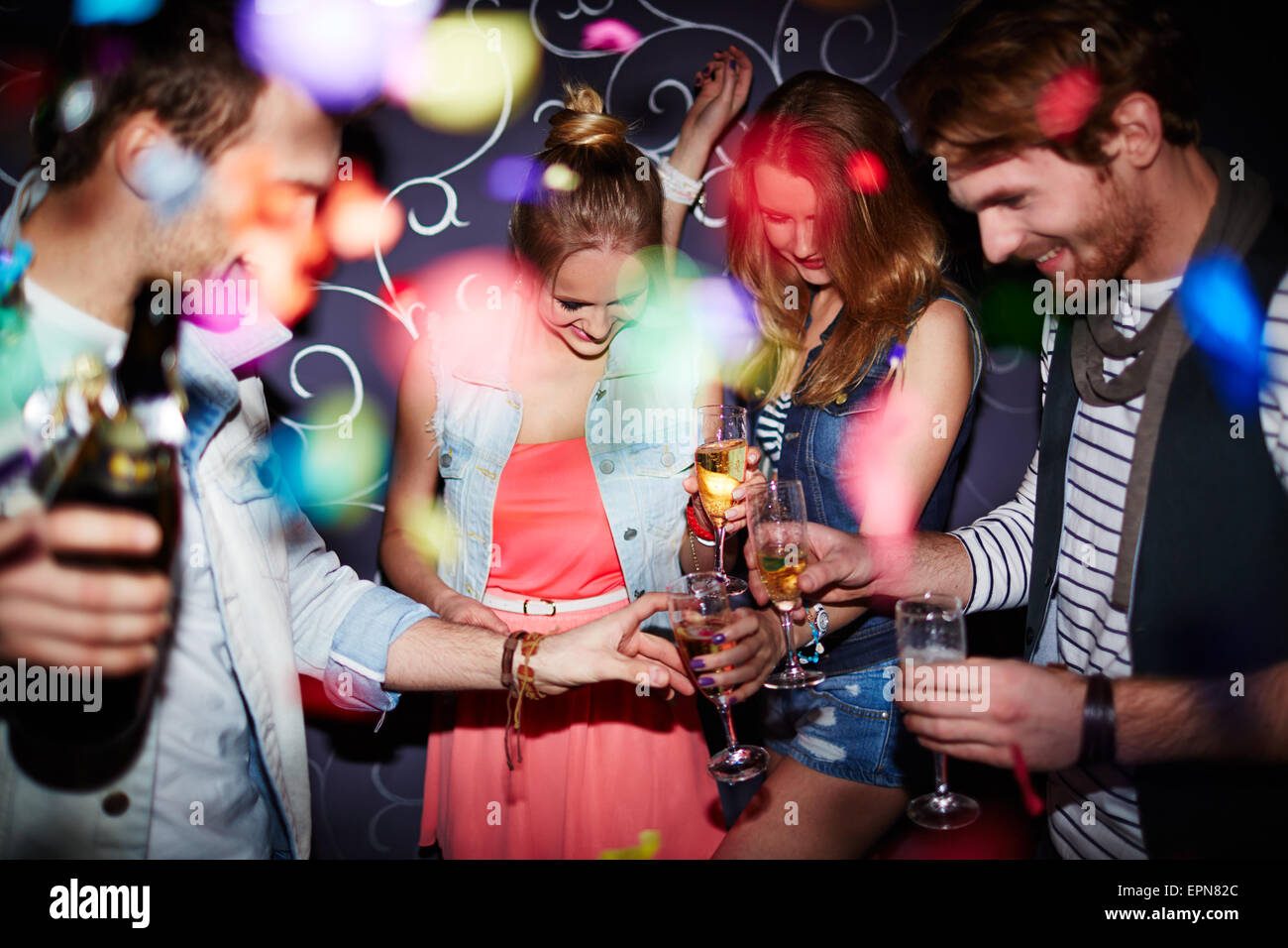 Group of young friends with flutes of champagne having party in club ...