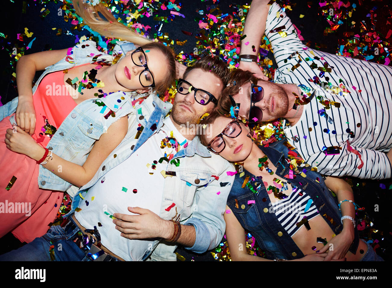 Young friends sleeping in confetti on the floor in nightclub after ...