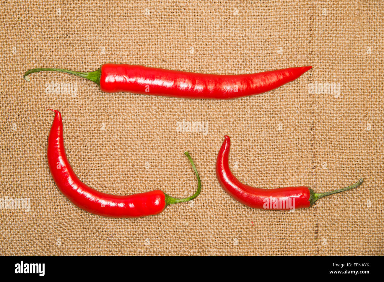 Three red Chile peppers on old cloth Stock Photo - Alamy