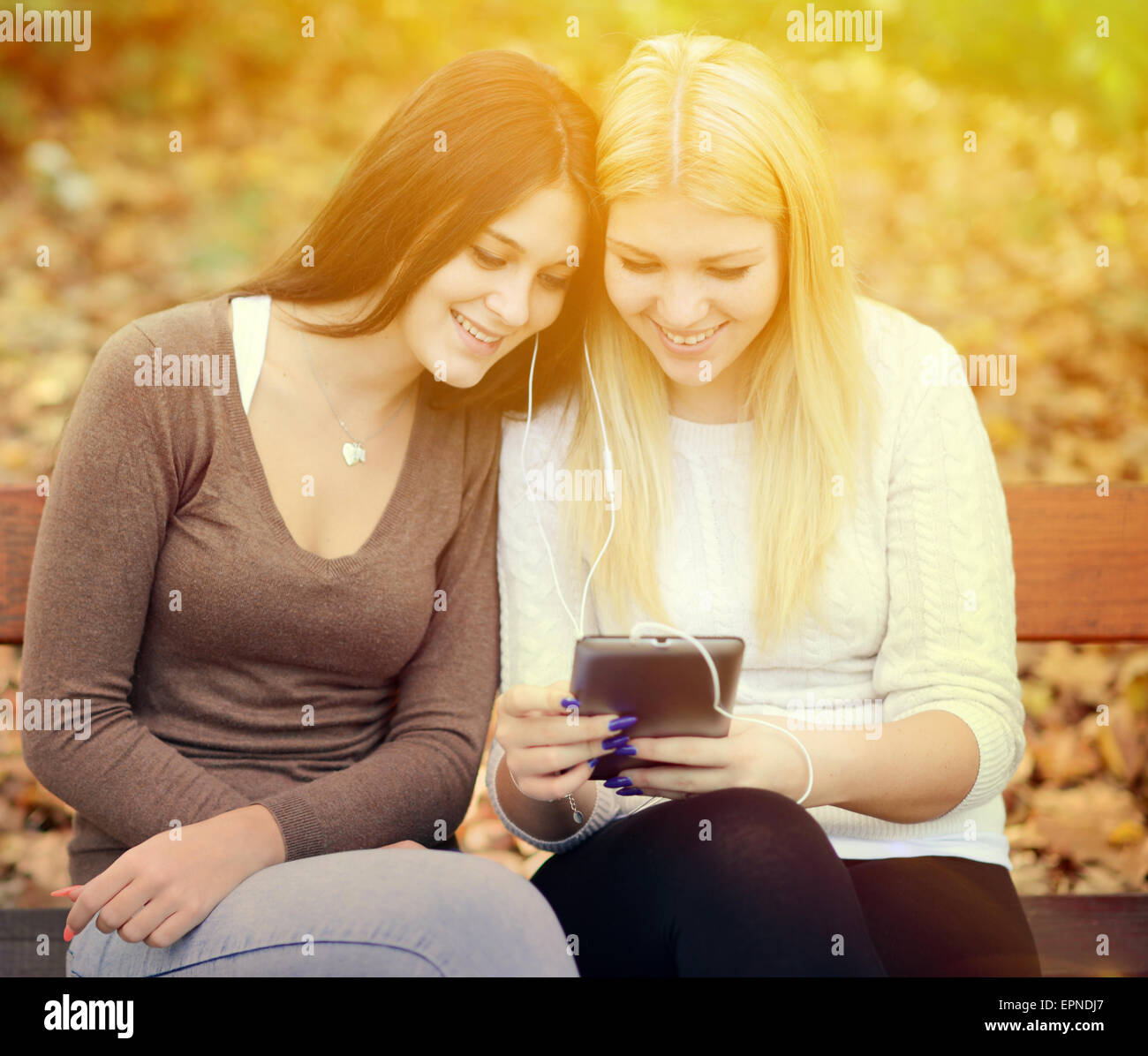 Two young women looking at tablet and chating online with friend Stock ...