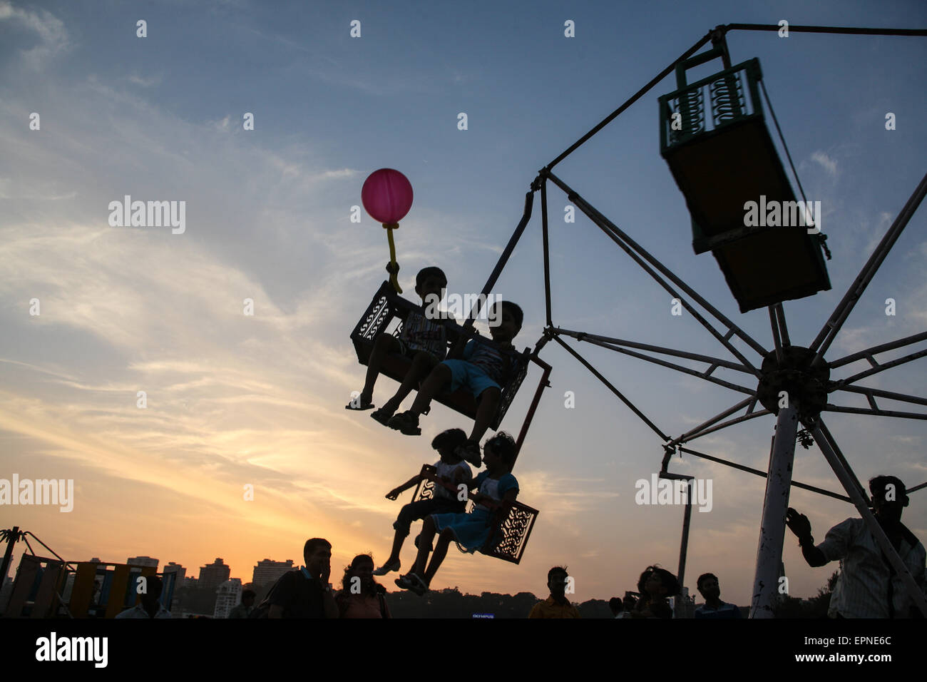 At sunset child with balloon and children on fair ground ride powered ...