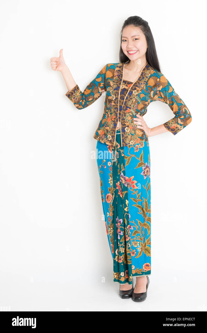 Full body portrait of Southeast Asian woman in batik dress giving thumb ...