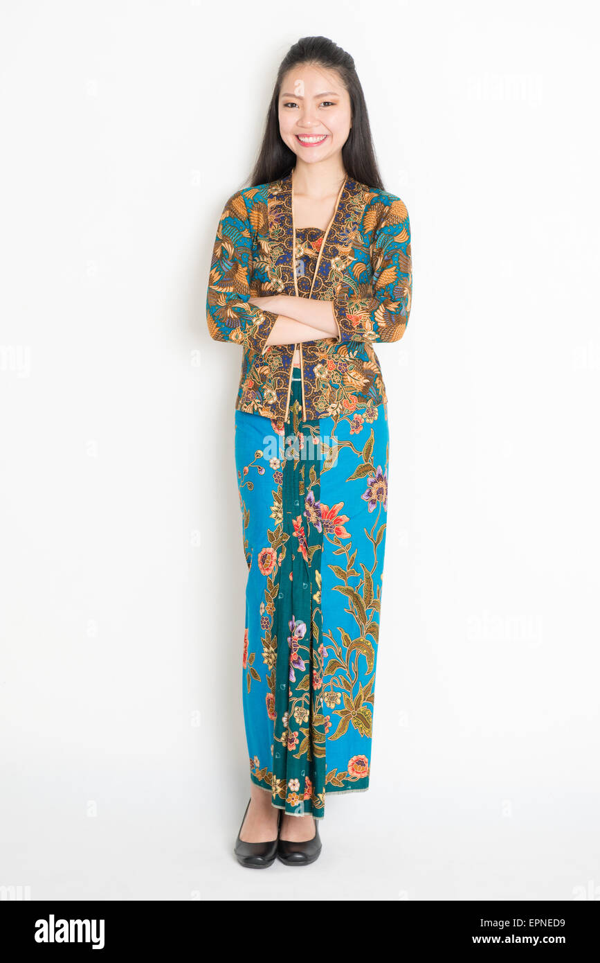 Full body Southeast Asian girl in batik dress standing on plain ...