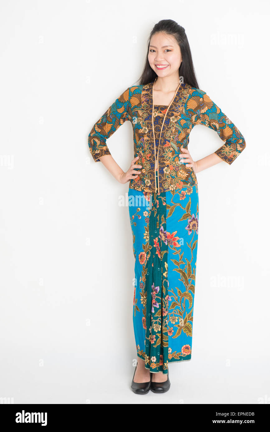 Full Body Southeast Asian Woman In Batik Dress Standing On Plain