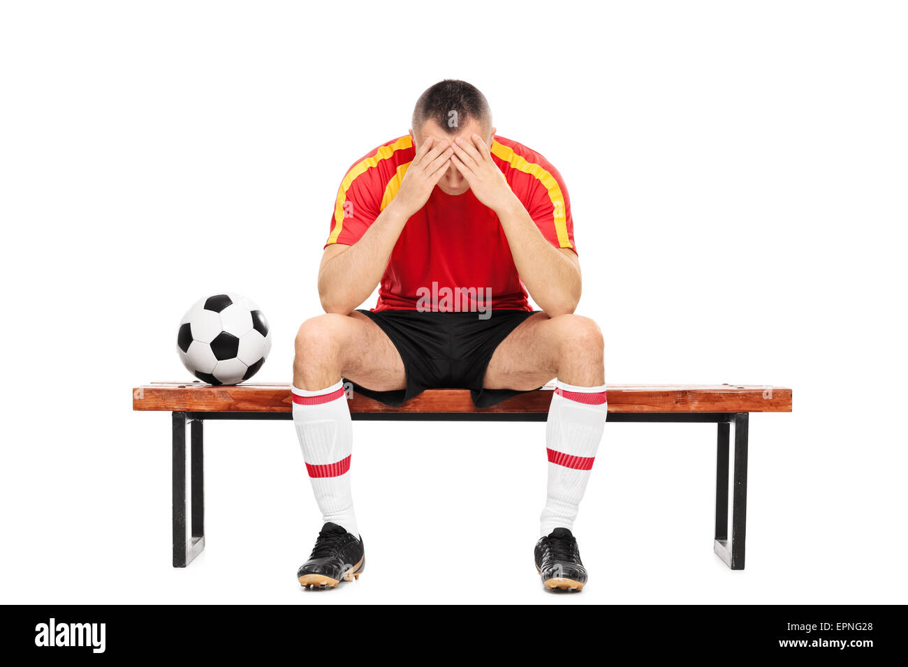 Worried young football player sitting on a wooden bench with his head ...