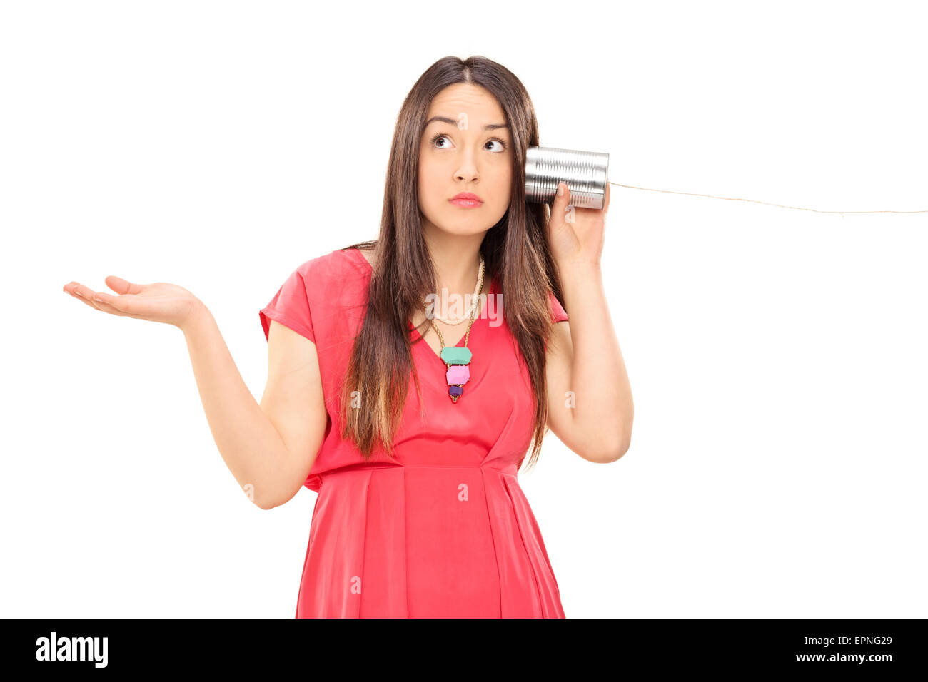 Young confused woman talking through a tin can phone and gesturing with ...