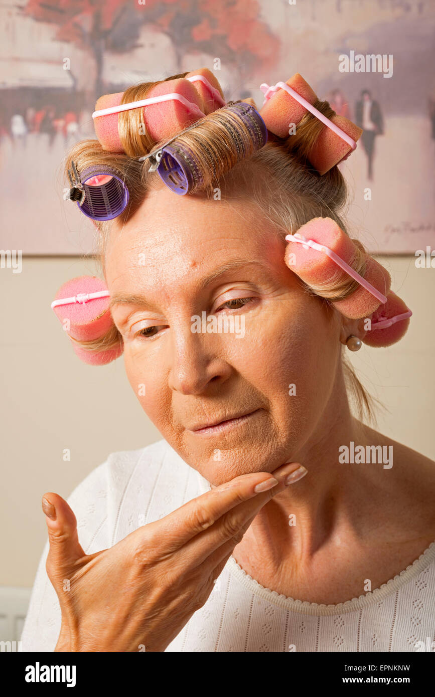 Woman in curlers applying makeup Stock Photo - Alamy