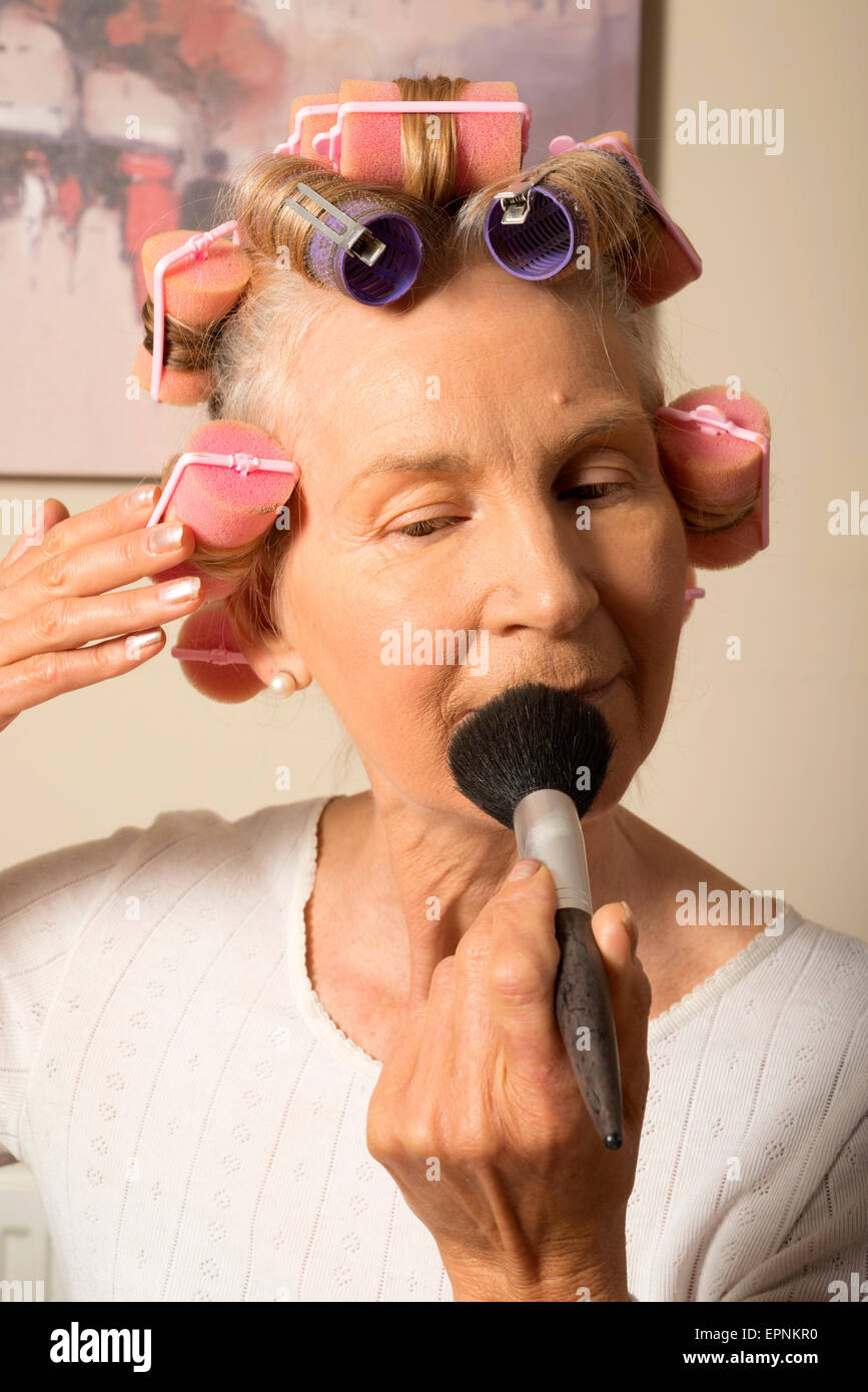 Woman in curlers applying makeup Stock Photo - Alamy