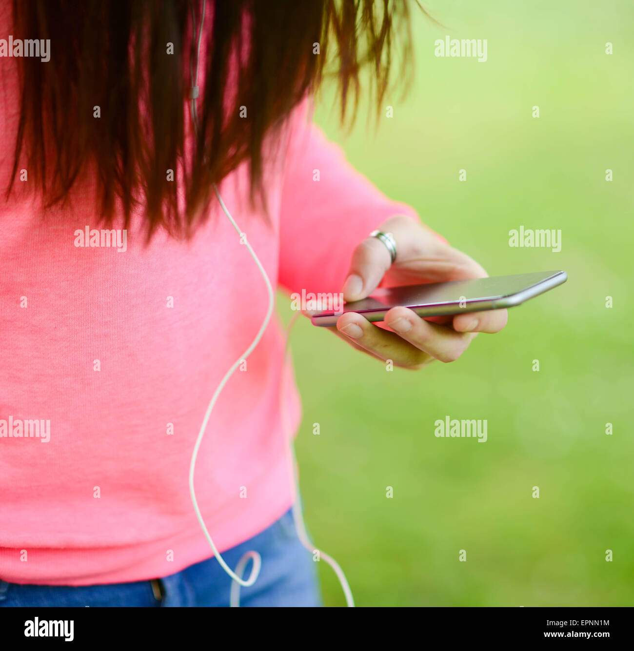 Girls hands holding cell phone while listening to music against green ...