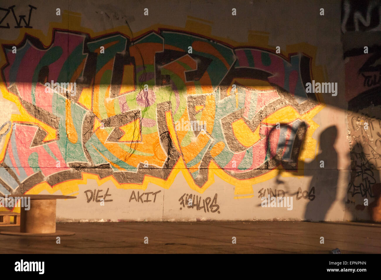 Shadows holding upturned bike in front of graffiti at Southbank London ...