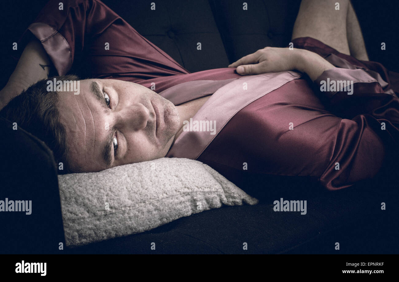 Man lying and resting on sofa at home. He is lost in thought with a ...