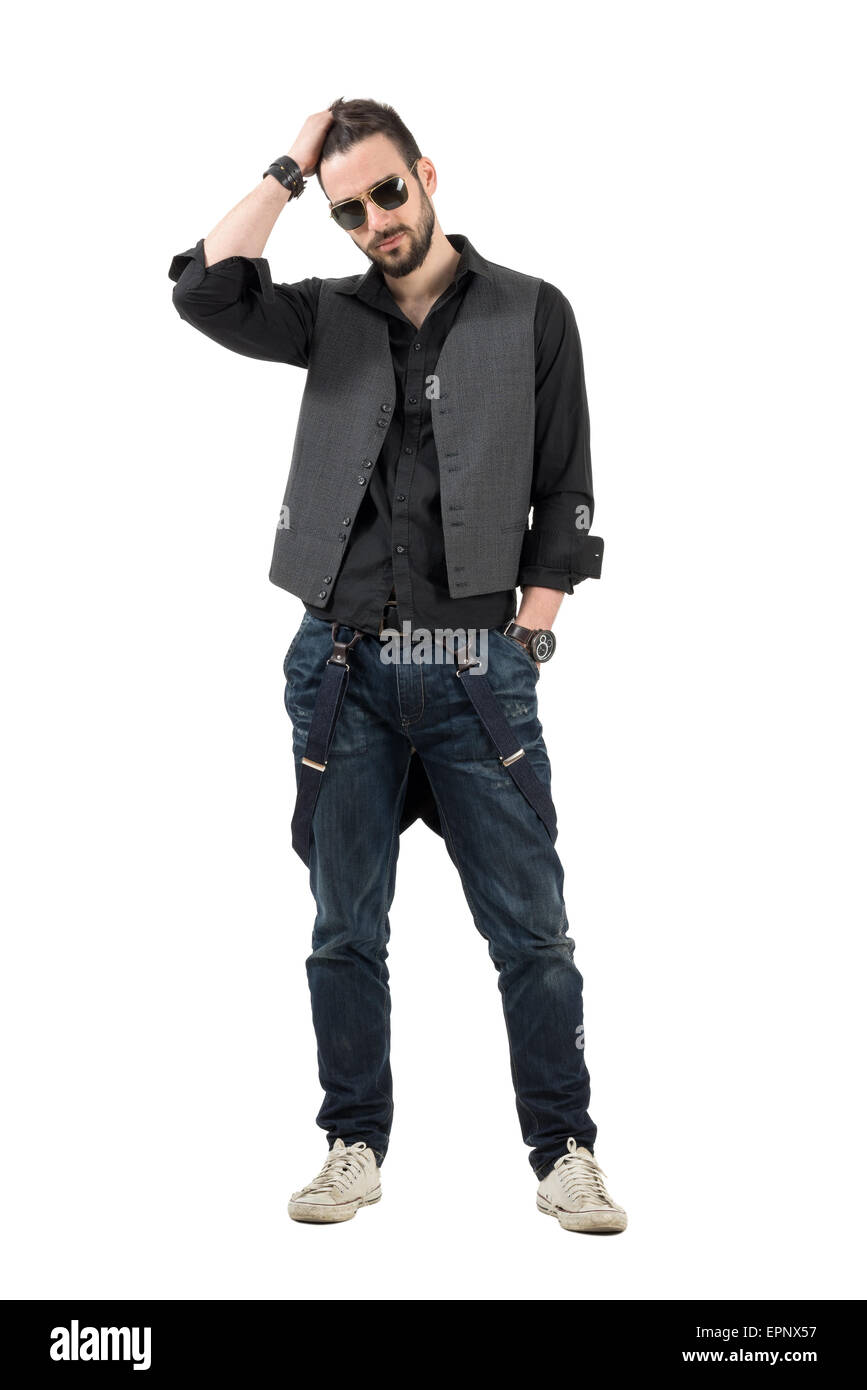 Serious young bearded man running fingers through hair looking at ...