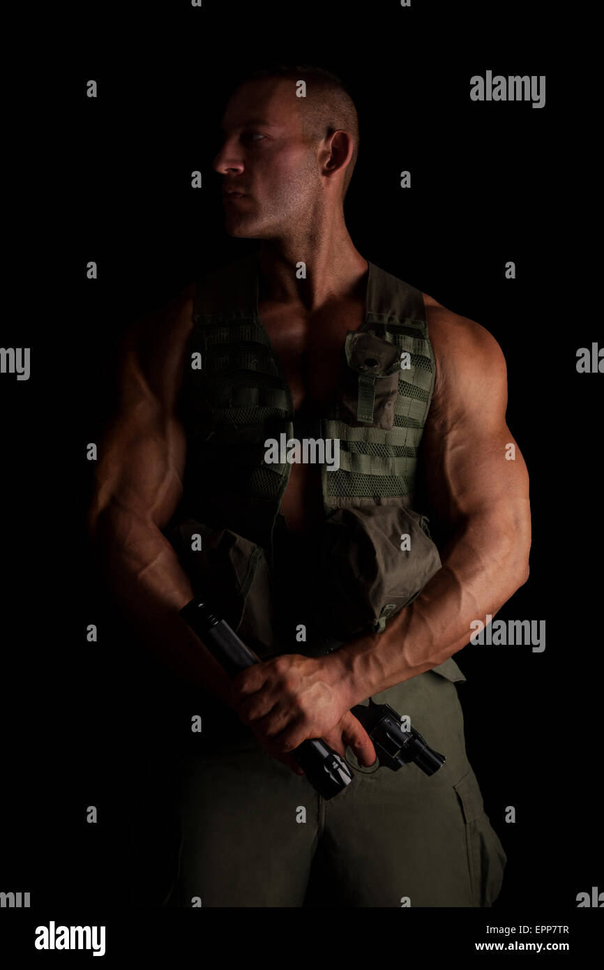 Young armed serious soldier in uniform standing proud against black ...