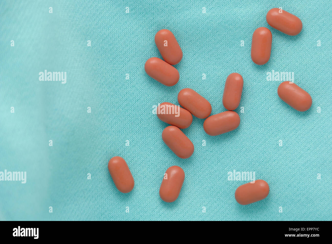 Maroon pills scattered across green blue background with copy space ...