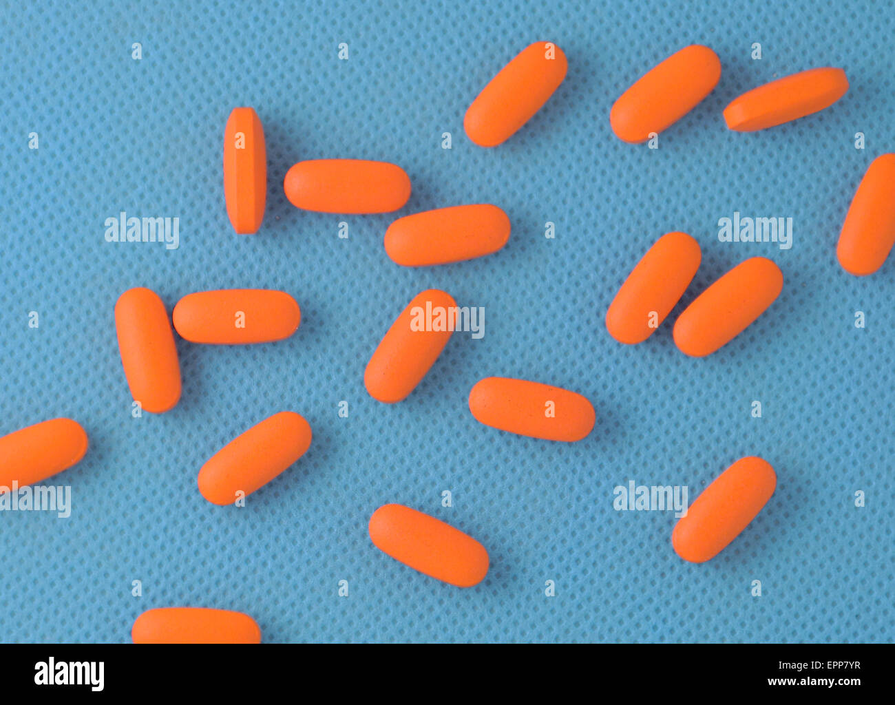 Orange medication scattered across a blue background Stock Photo - Alamy
