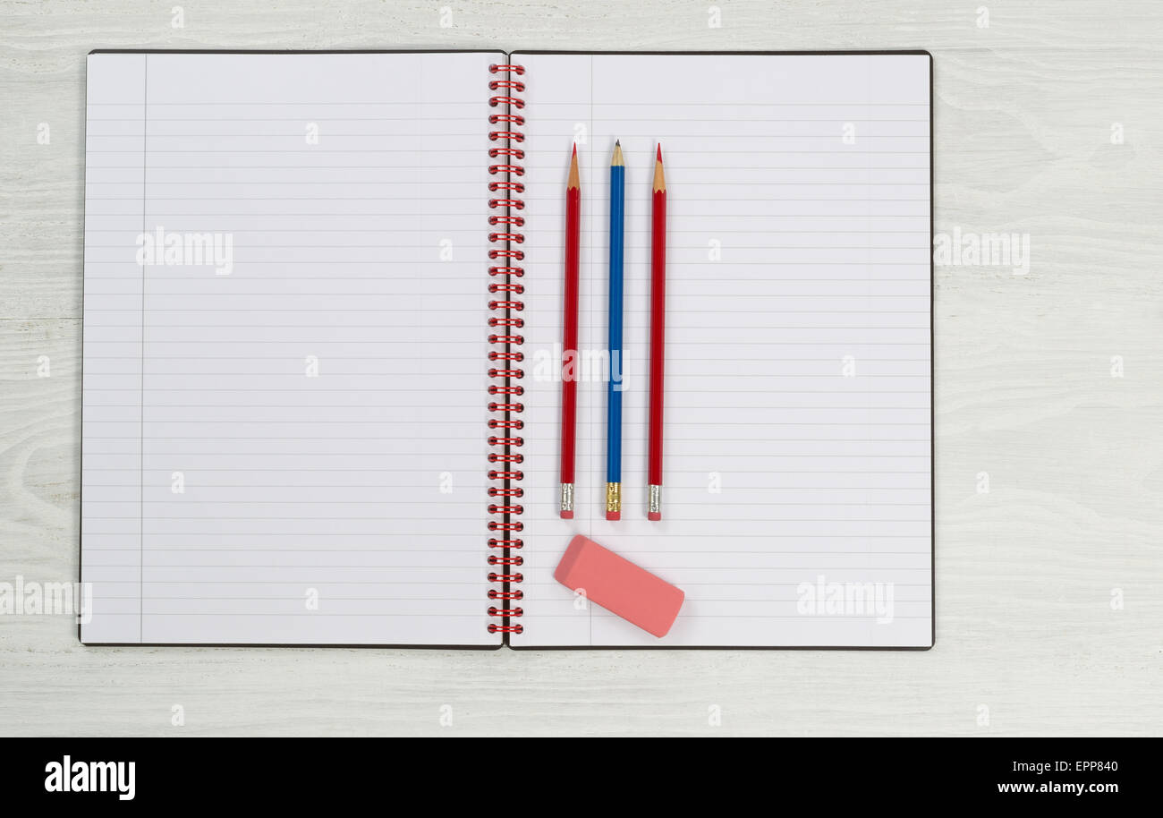 Blank new notepad, in open position, with sharpen pencils and eraser on ...